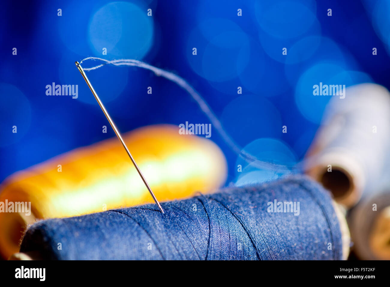 needle and blue and yellow thread on the blue background Stock Photo - Alamy