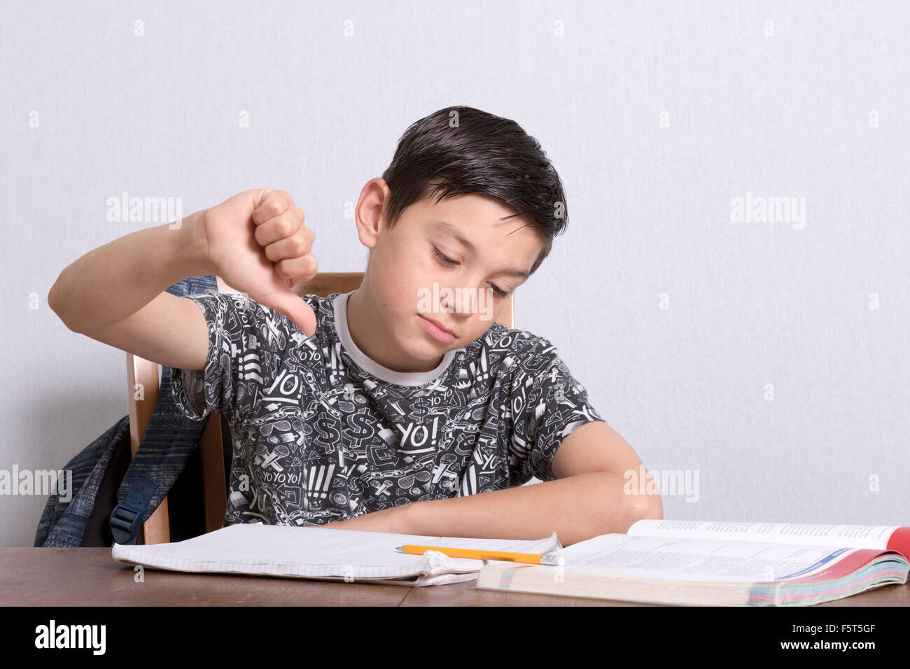 Young boy giving thumbs down over homework Stock Photo - Alamy