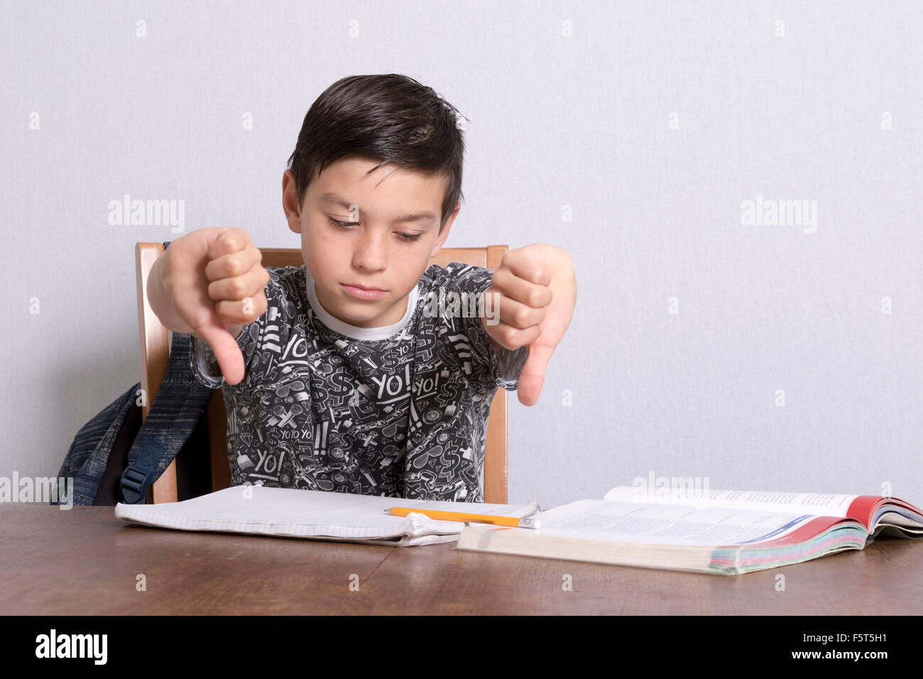 Young boy giving thumbs down over homework Stock Photo - Alamy