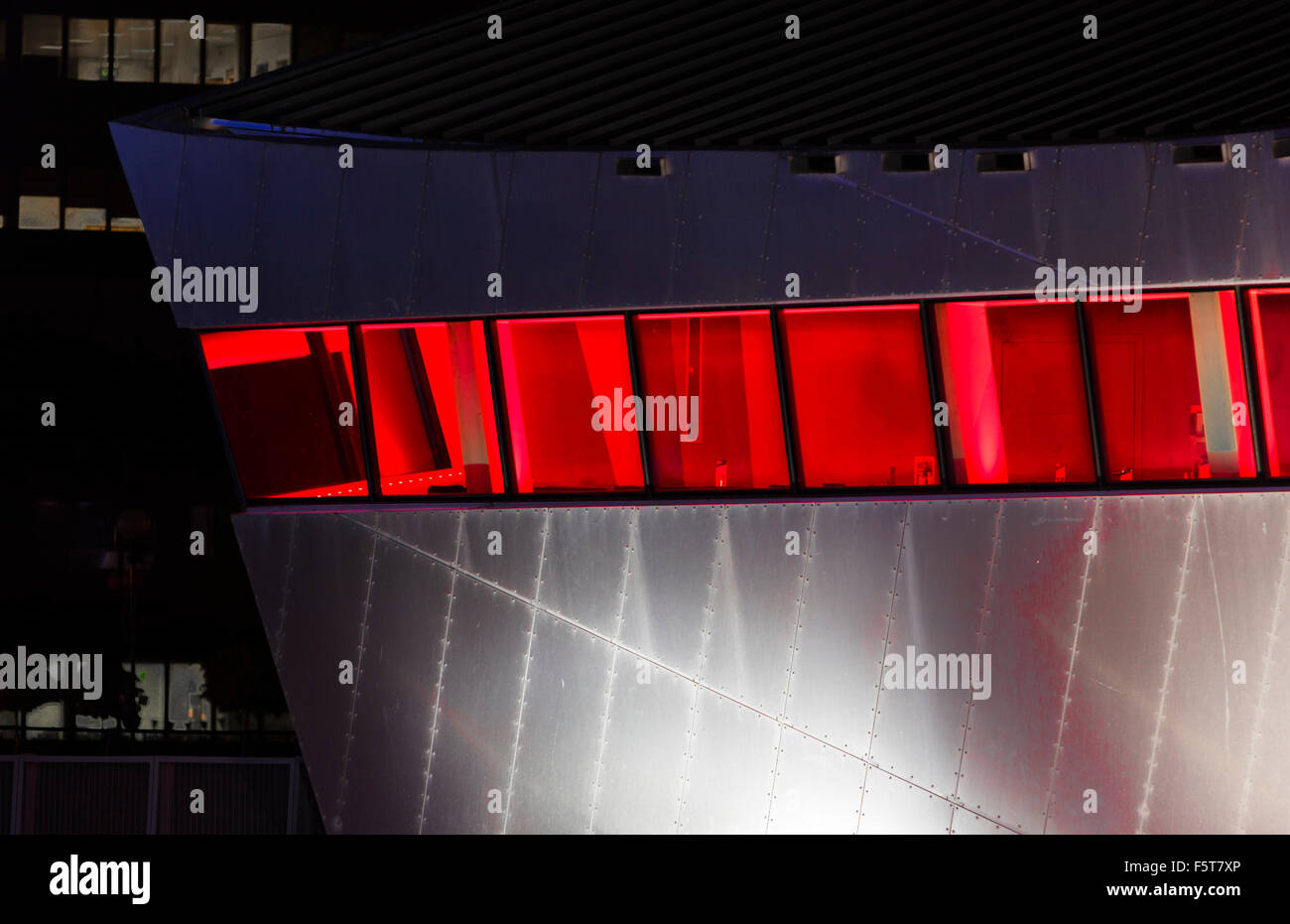 Red windows on a stainless steel building at night Stock Photo - Alamy