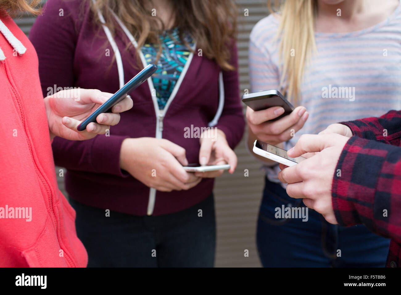 Group Of Teenagers Sharing Text Message On Mobile Phones Stock Photo ...