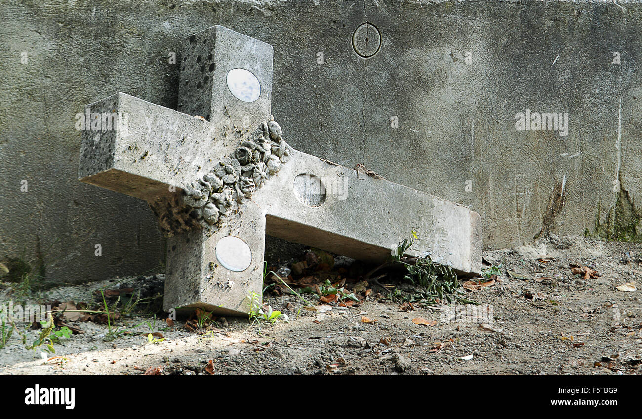 A cross, used as a gravestone, fallen and propped against a wall in the ...