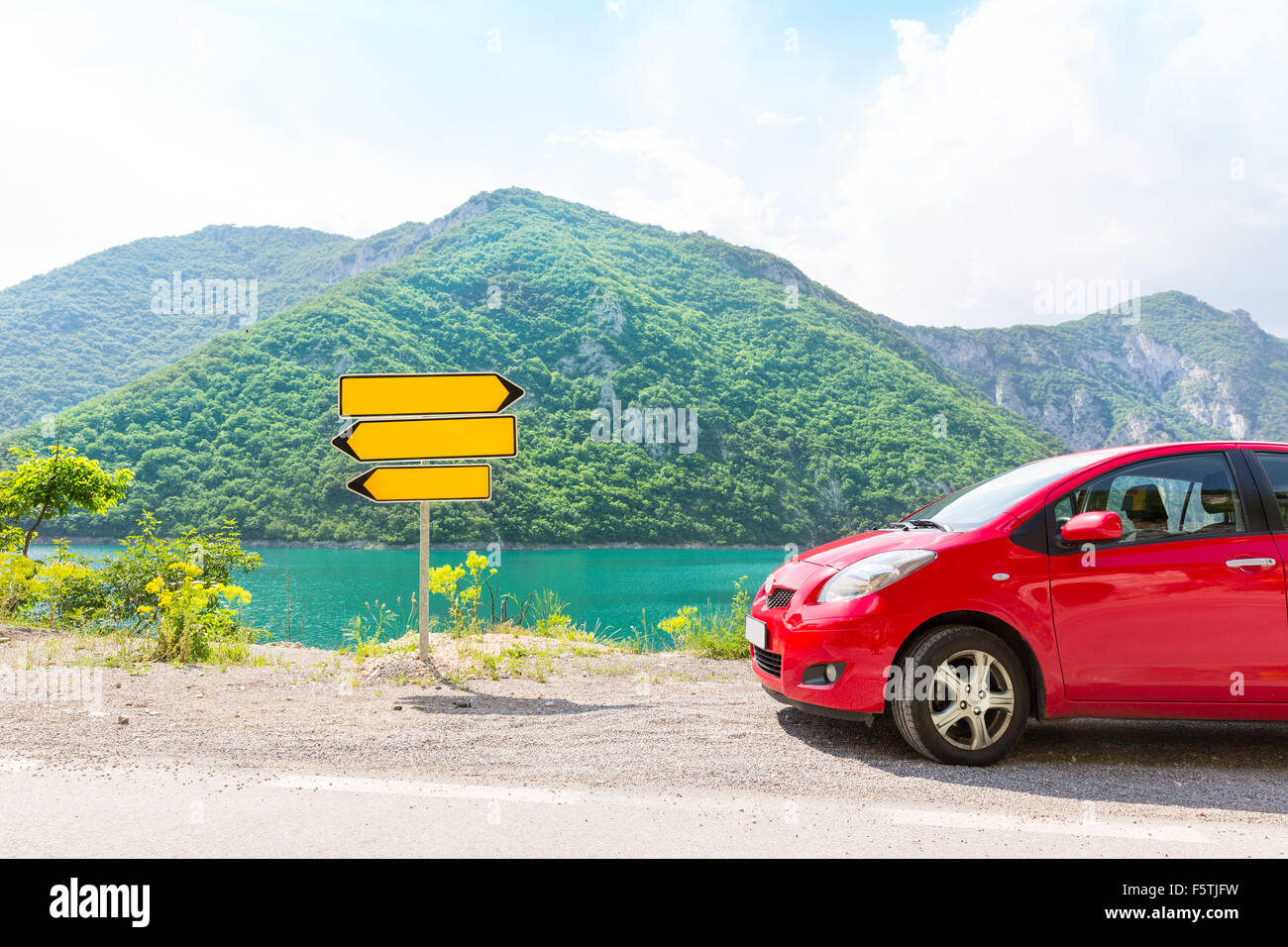 Red car in mountains and road pointer Stock Photo - Alamy