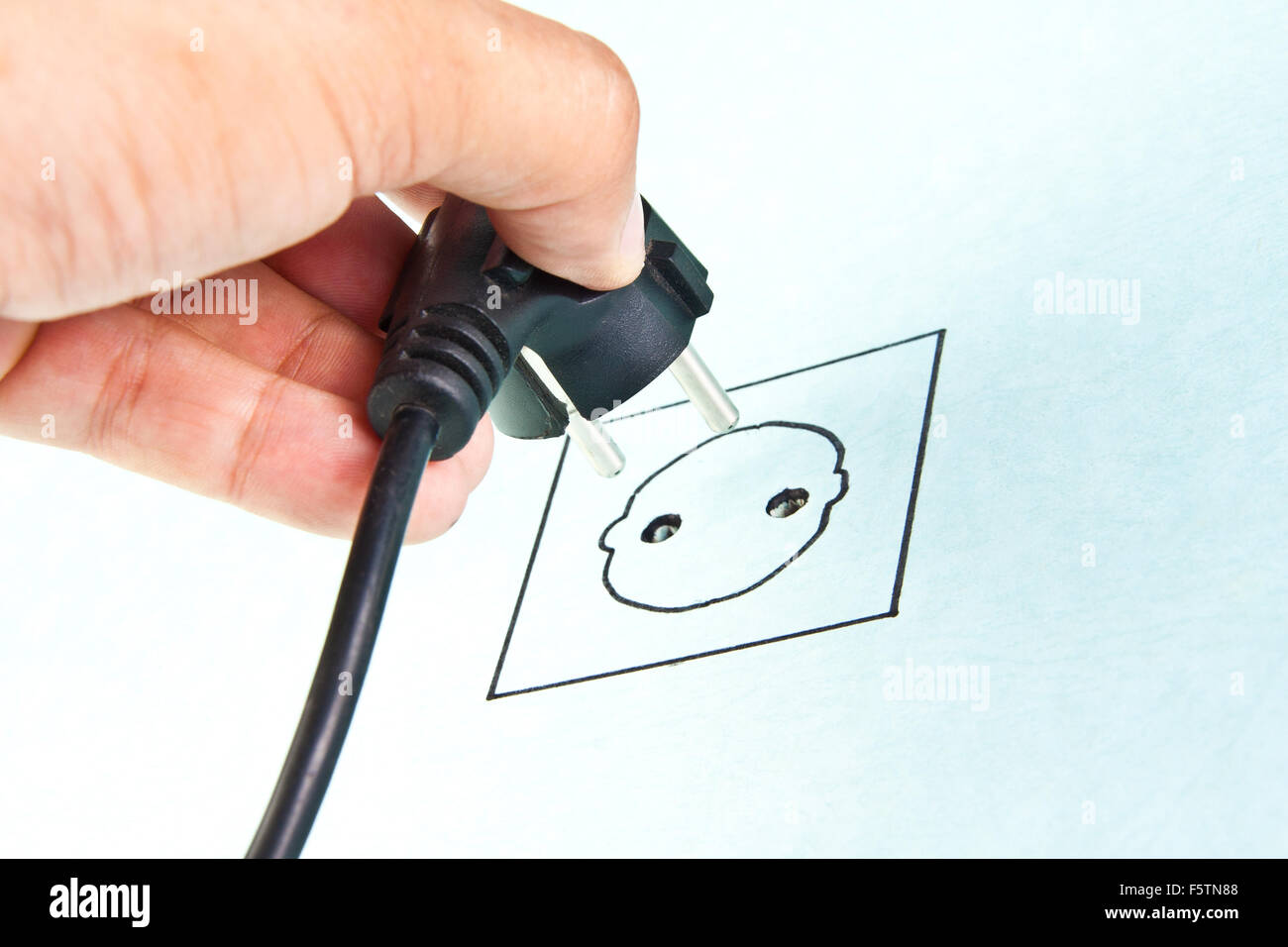 Plugging electrical cable to sketching socket on the wall Stock Photo ...