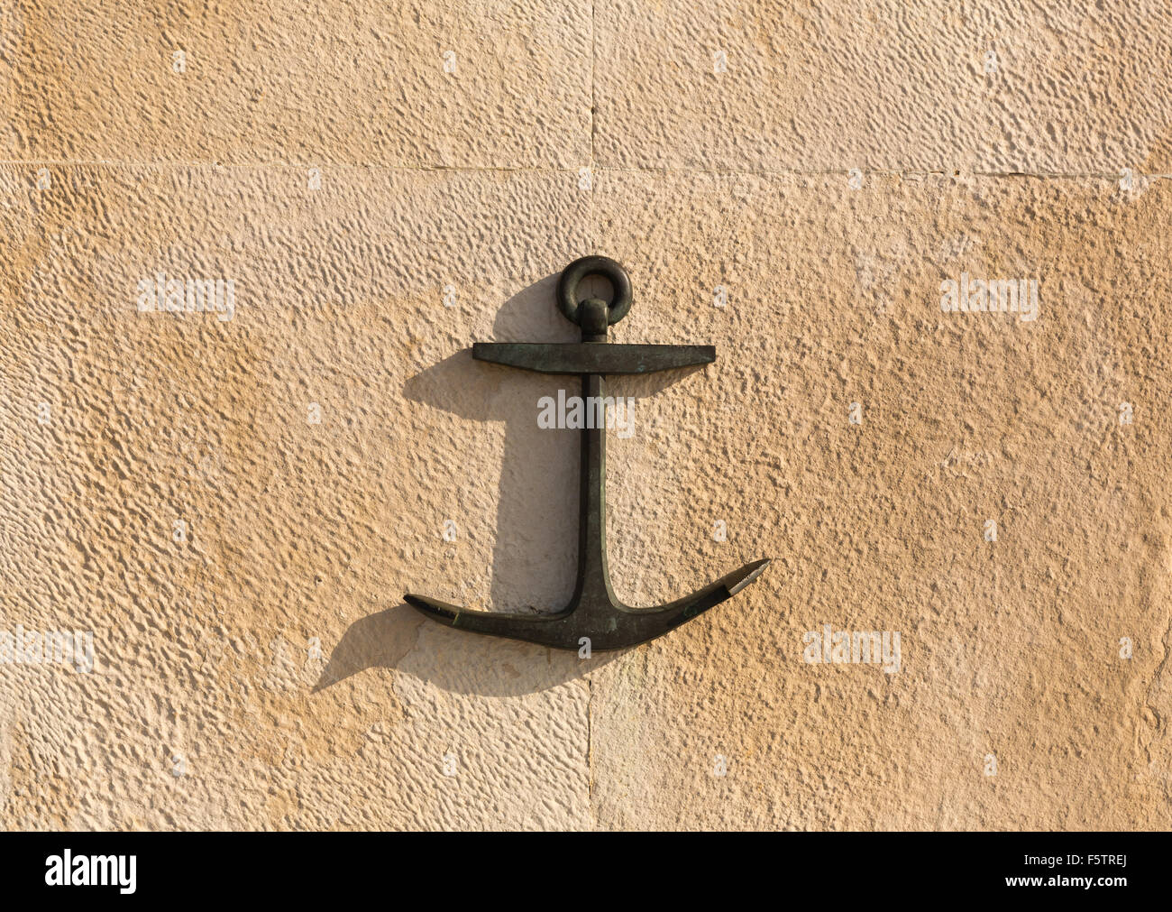 Black anchor on the stone wall Stock Photo - Alamy