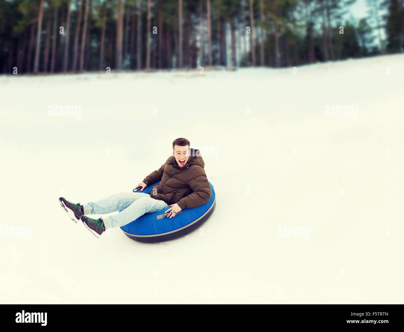 happy young man sliding down on snow tube Stock Photo - Alamy
