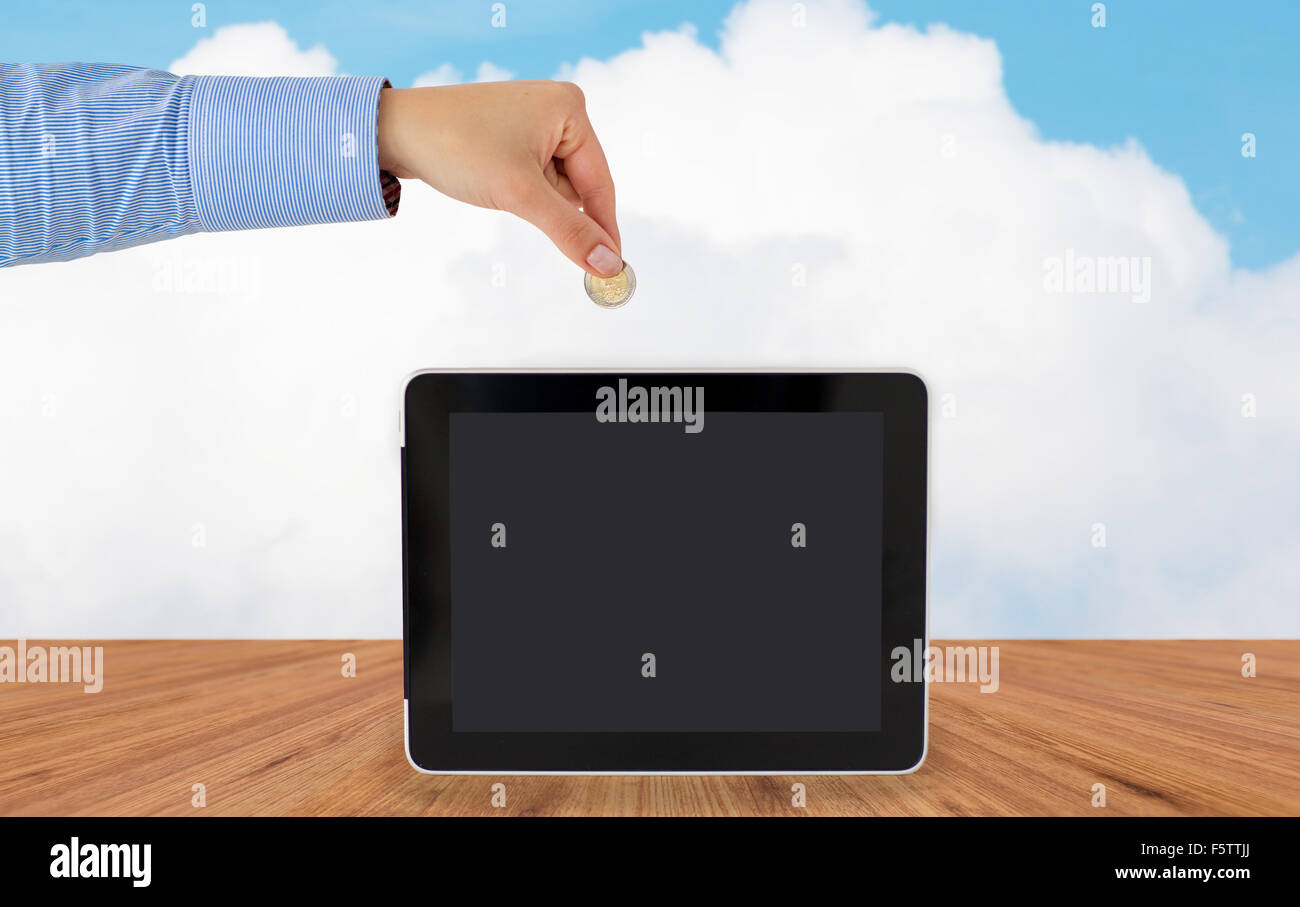 close up of hand putting coin into tablet pc Stock Photo - Alamy