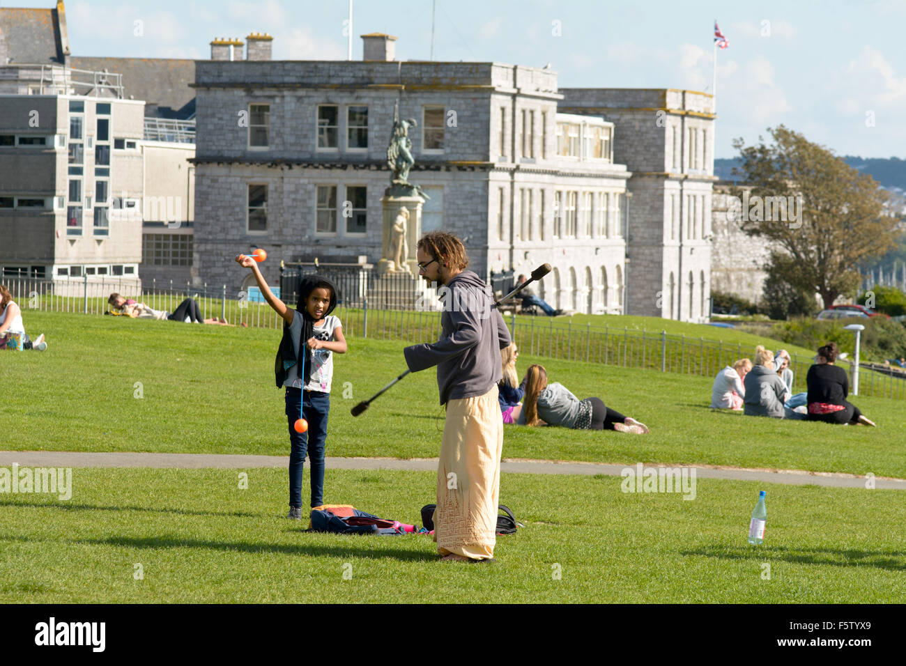 Man teaching youngster how to use fire performance long pole in daytime ...