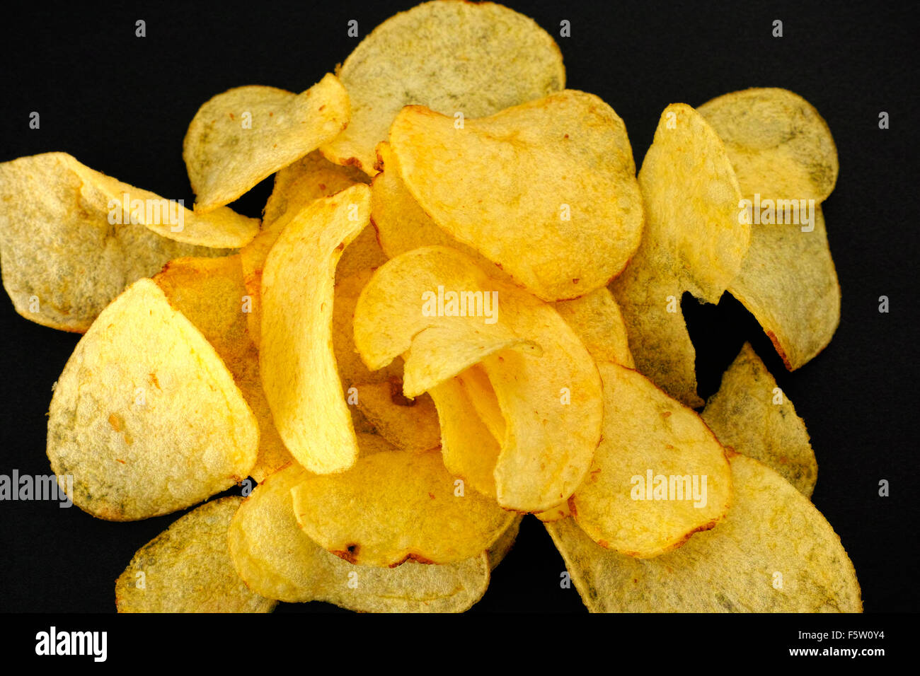 Heap of potato chips on black background Stock Photo - Alamy