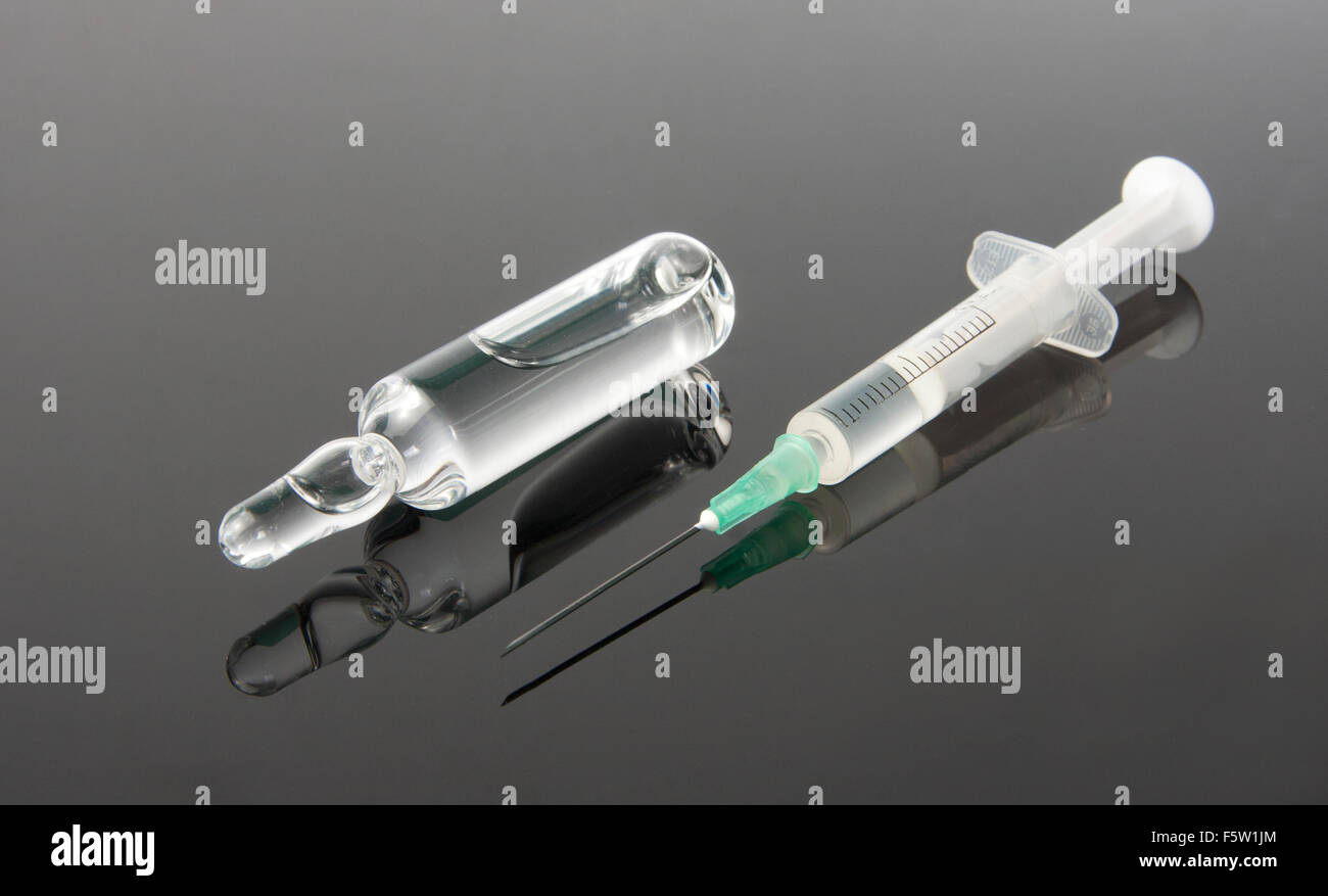 Medicine and syringe on gray surface Stock Photo - Alamy