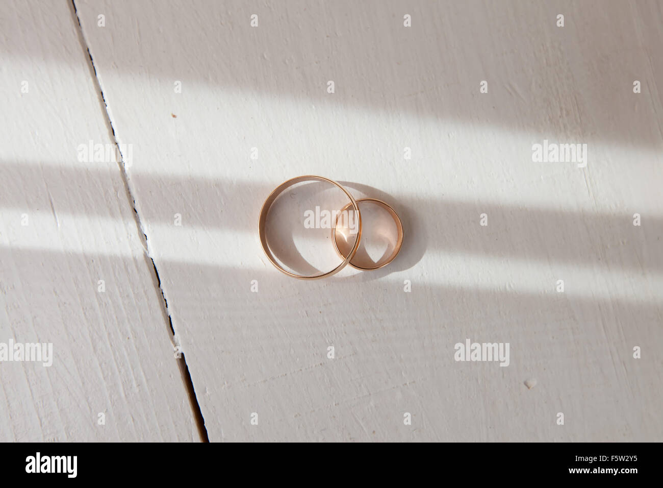 Gold wedding rings on a white table in the sun Stock Photo - Alamy