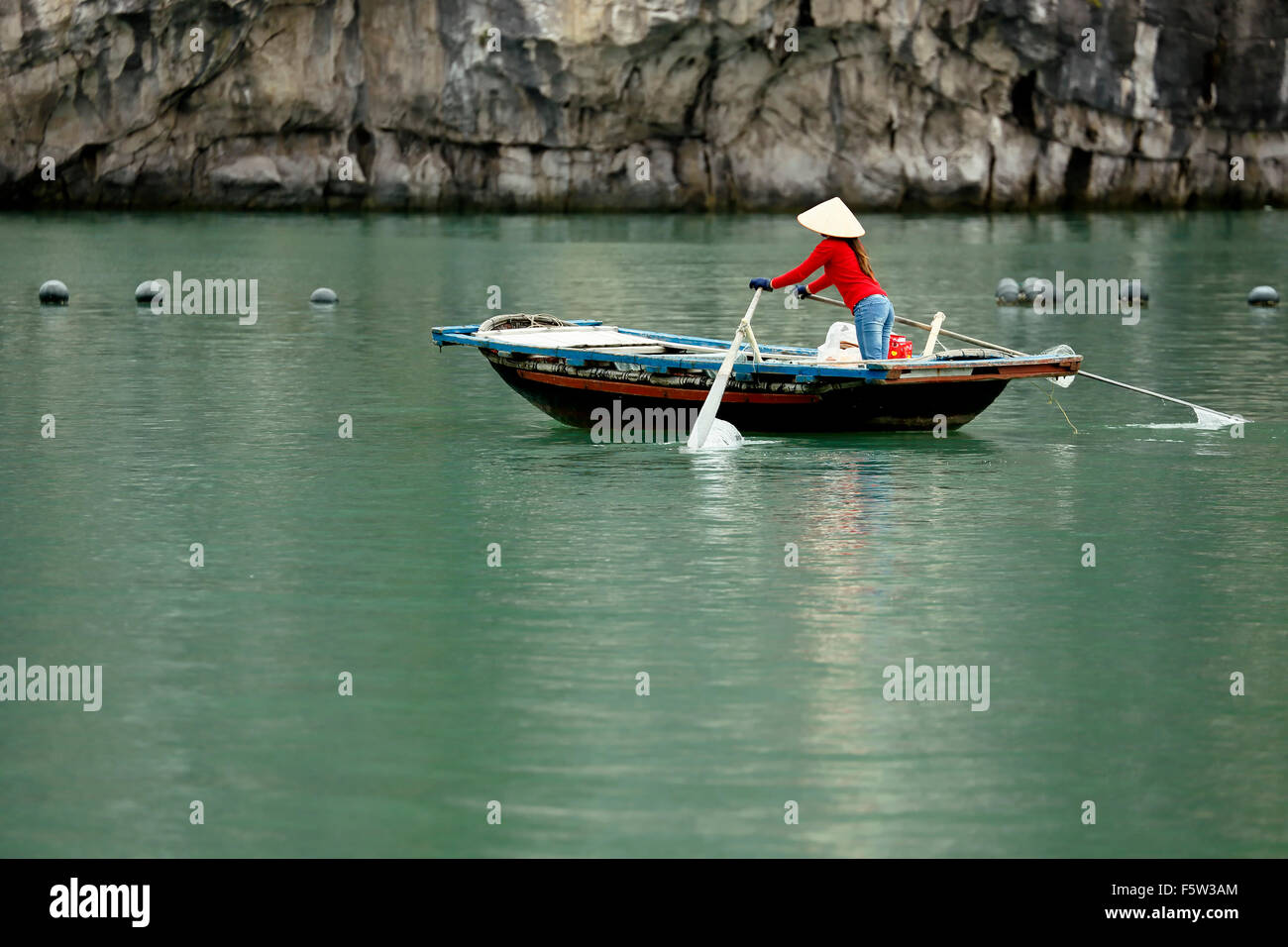 Woman in wooden rowboat and pearl farm buoys, Vung Vieng fishing ...