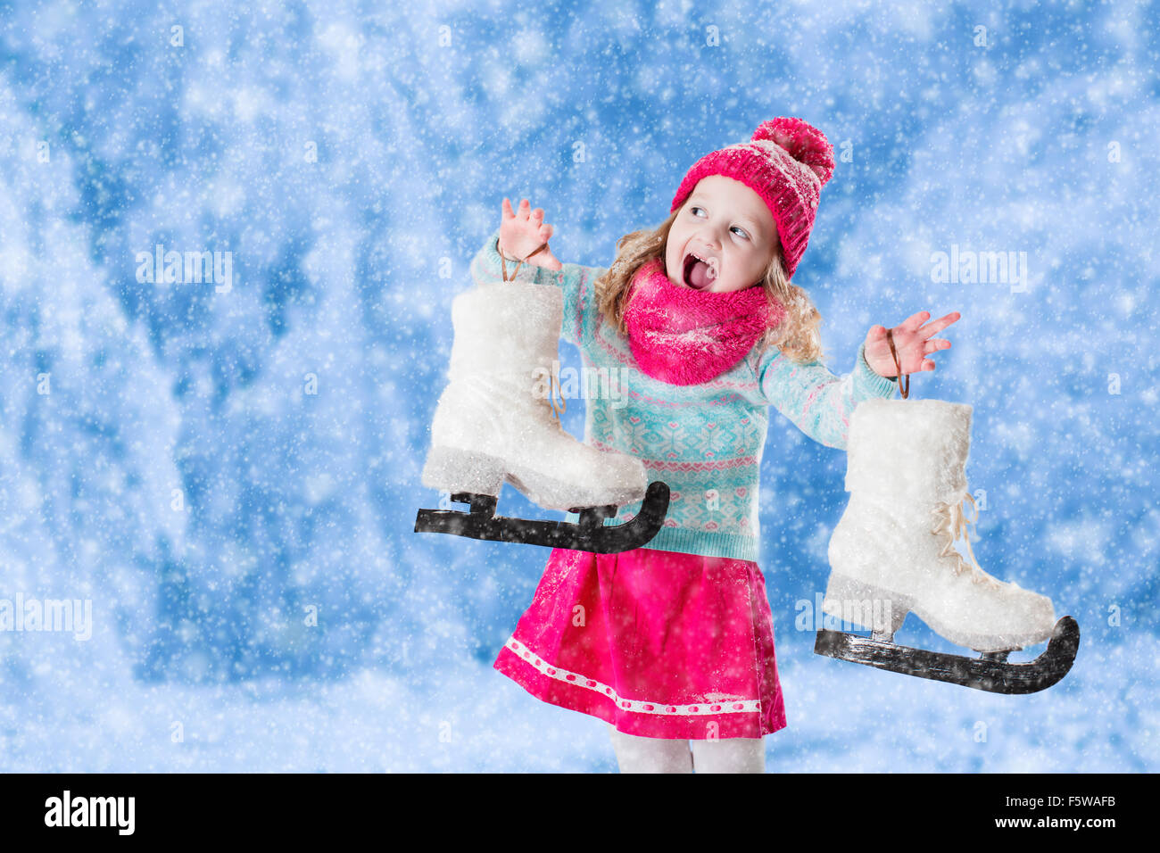 Happy laughing little girl having fun ice skating in snowy park. Winter ...