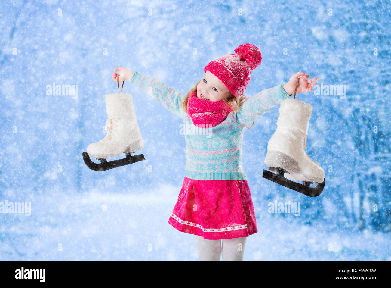 Happy laughing little girl having fun ice skating in snowy park. Winter ...