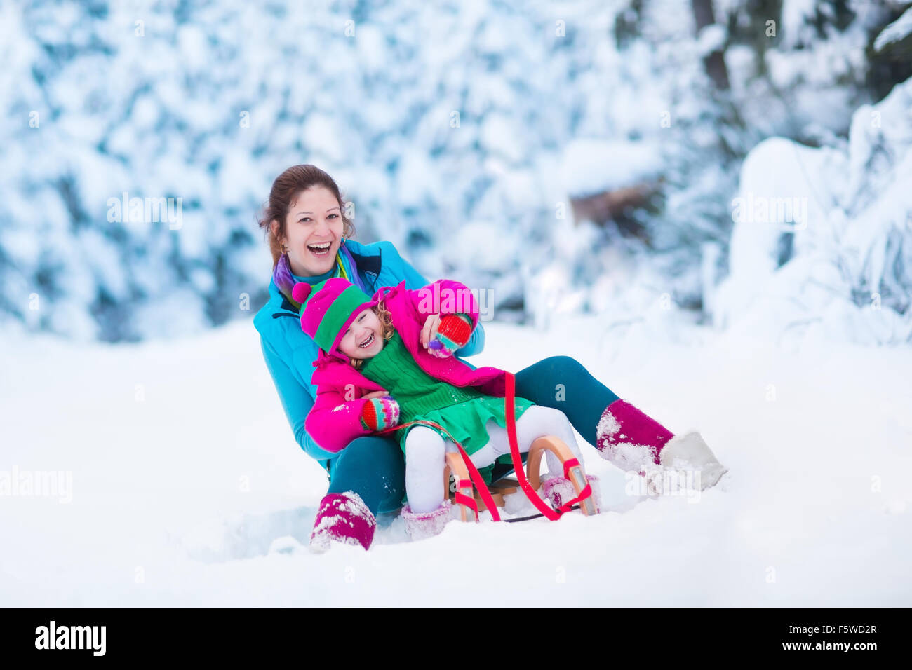 Young mother and little girl enjoying sleigh ride. Child sledding ...