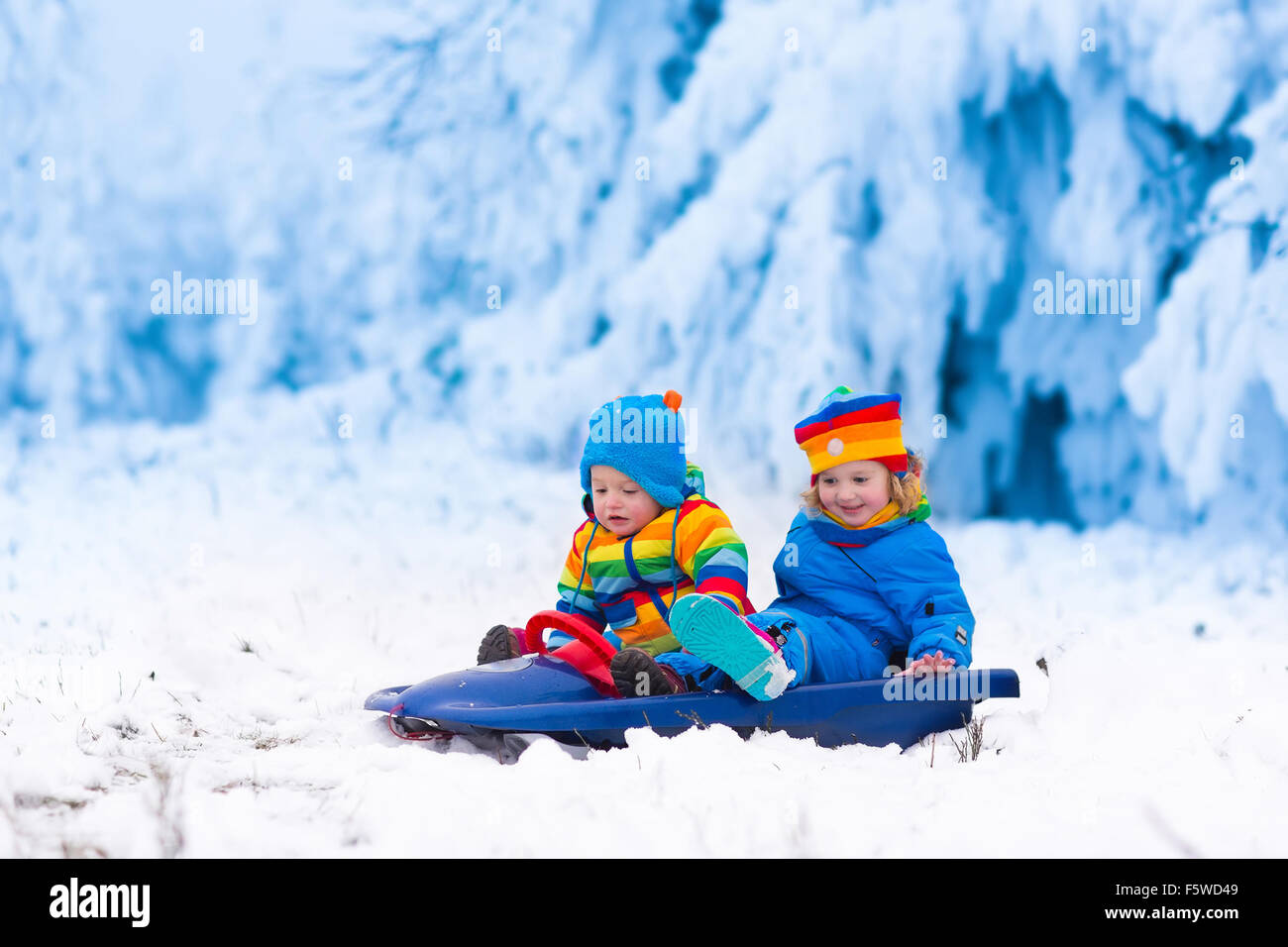 Little girl and boy enjoy a sleigh ride. Child sledding. Toddler kid ...