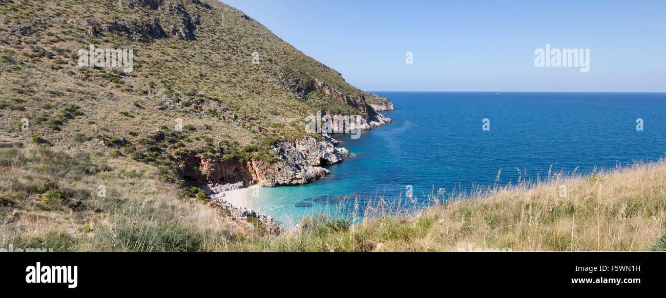 Path and small palm trees with barren mountains and pristine blue sea ...