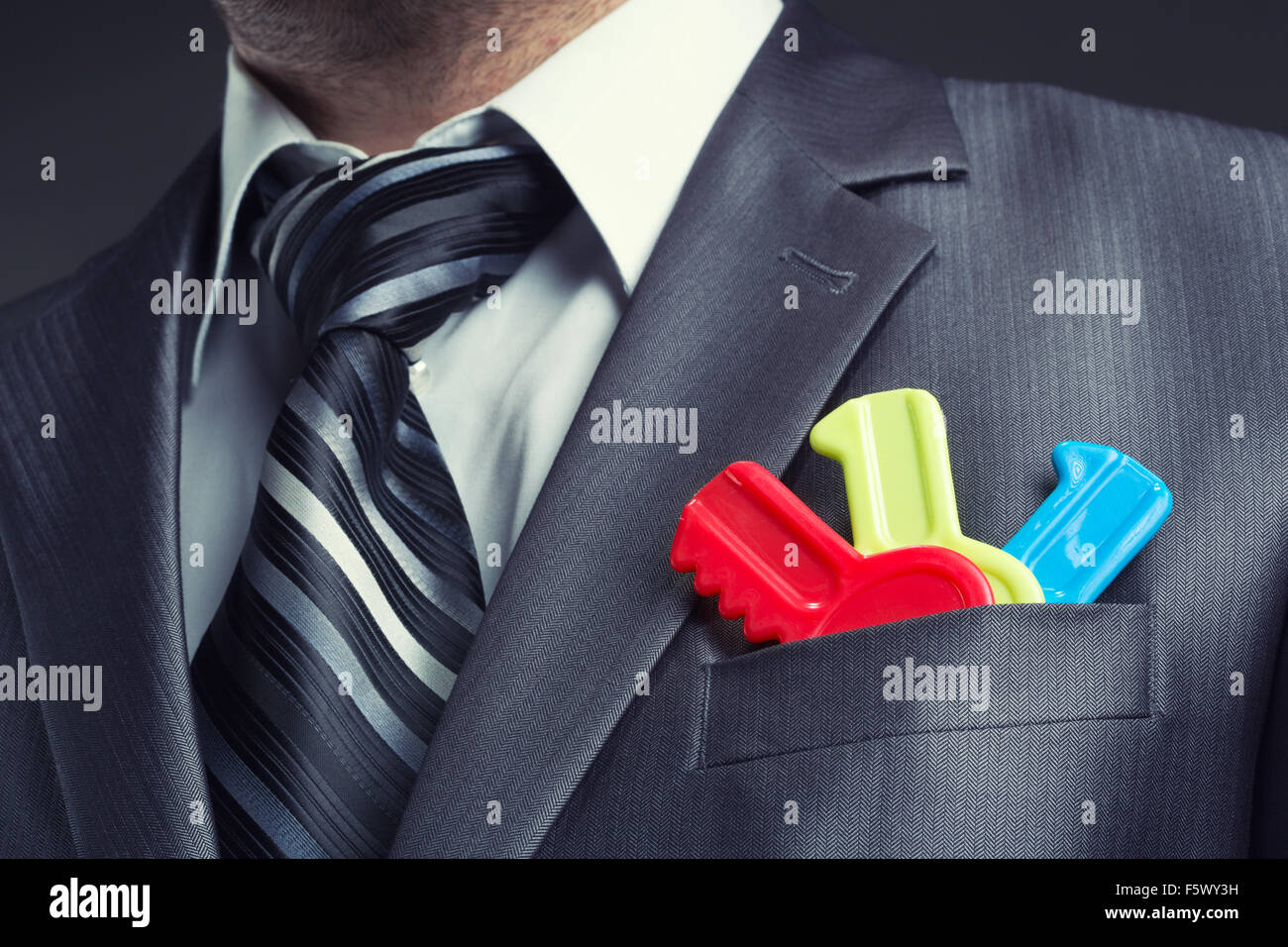 Businessman with colorful toy keys in suit pocket Stock Photo - Alamy