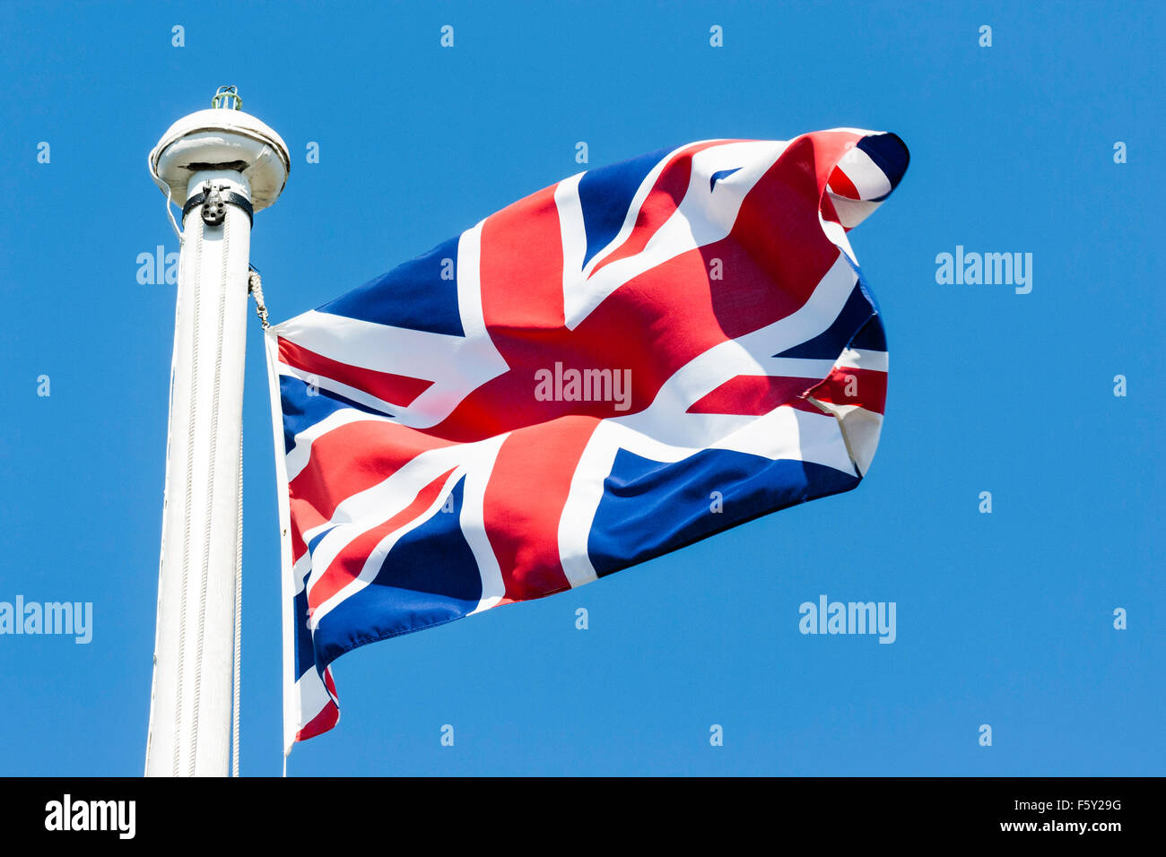 Union Jack flying and fluttering in the wind atop flagpole, with clear ...