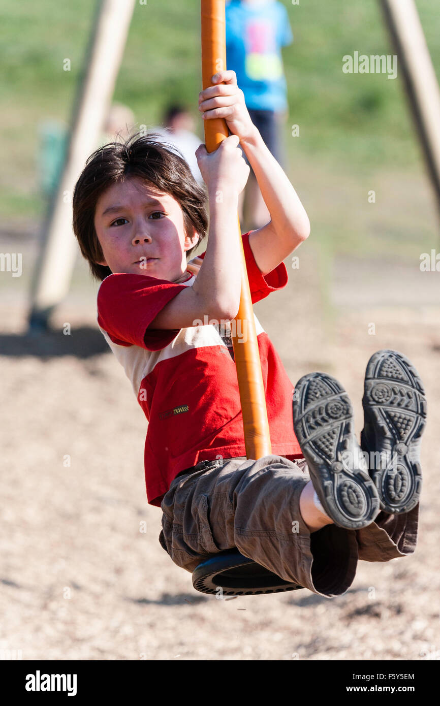 Caucasian child, boy, 7-8 year old, clinging on with both hands to rope ...