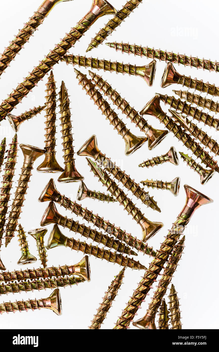 Gold coloured wood cross head screws laying scattered on top of ...