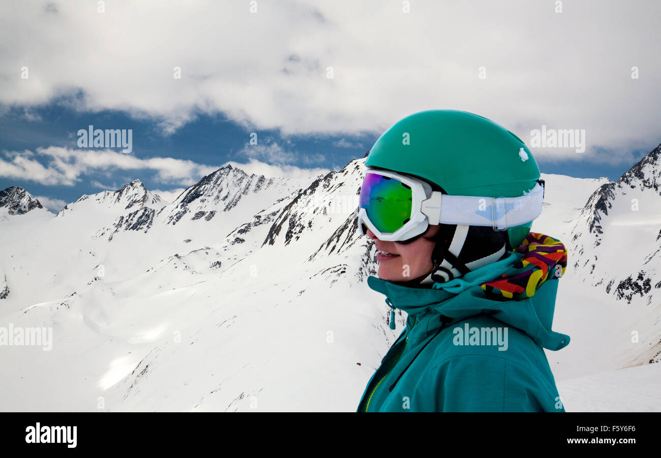 portrait of a smiling girl in helmet and mask on snow-capped mountains ...