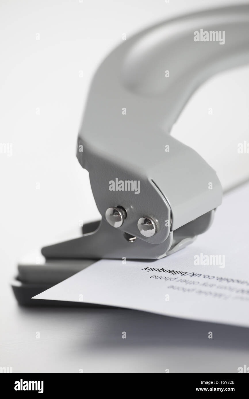 A paper whole punch with a sheet of paper on a white background Stock ...
