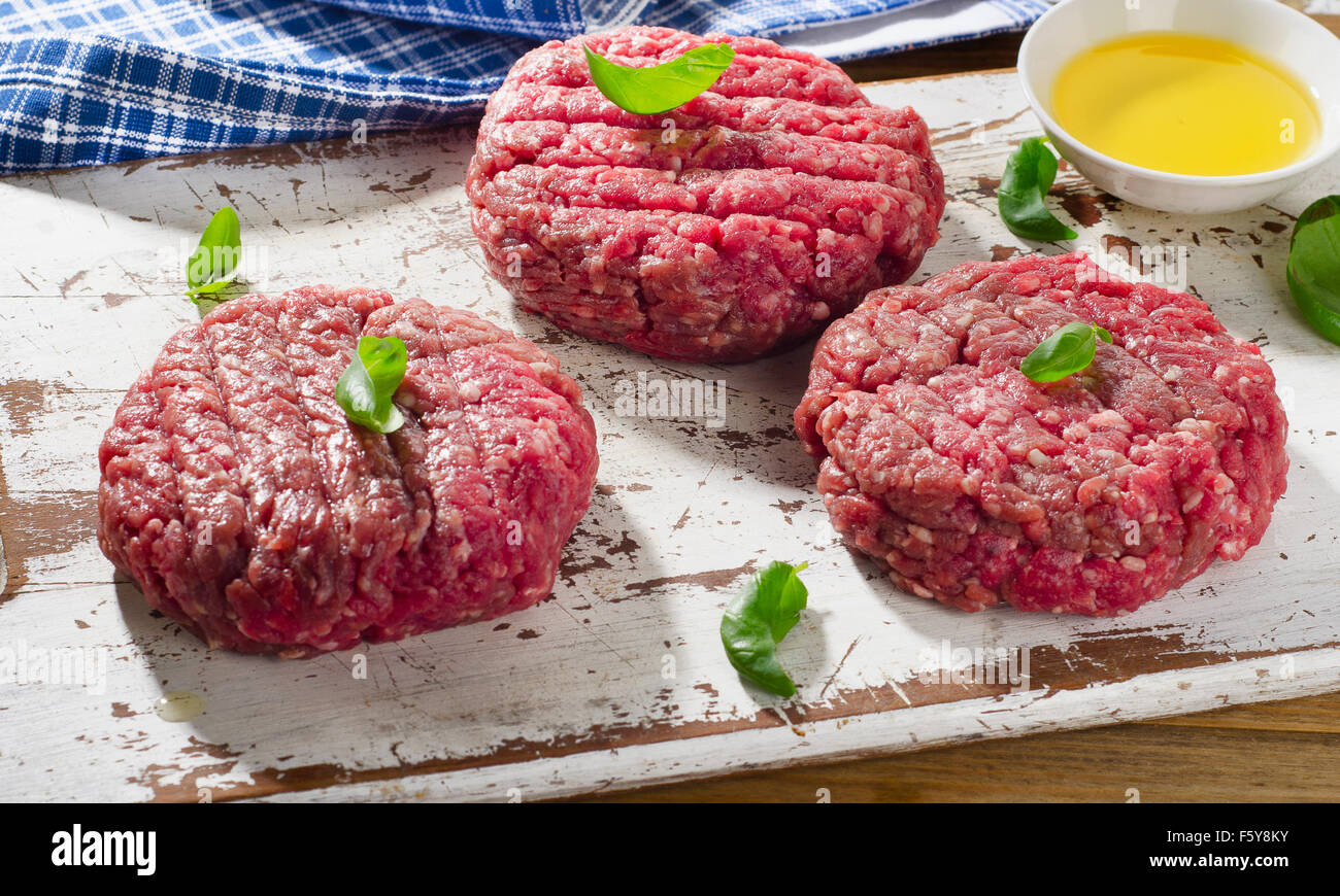 Raw ground beef patties on a white wooden board Stock Photo - Alamy