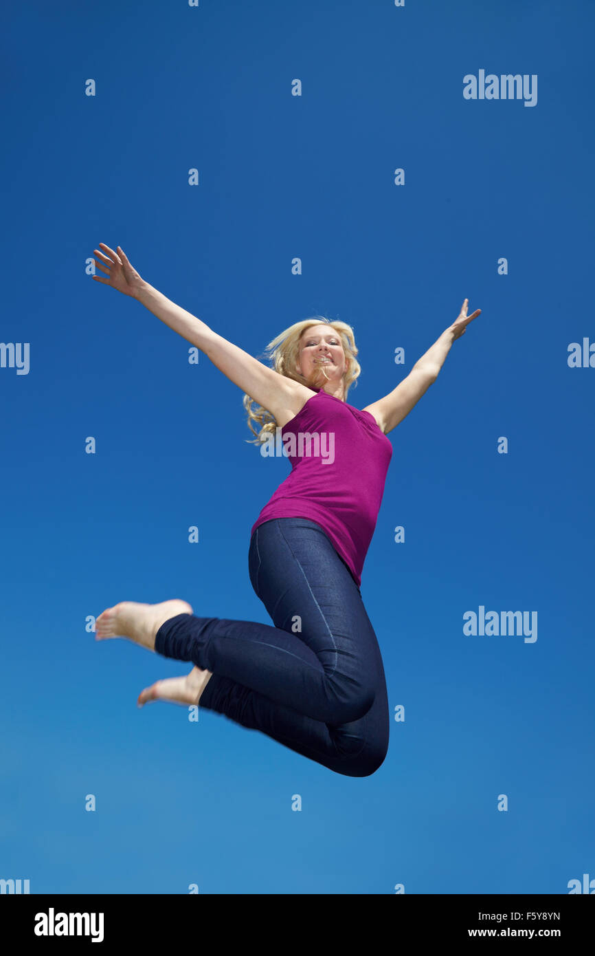 Happy young woman jumping into the air Stock Photo - Alamy