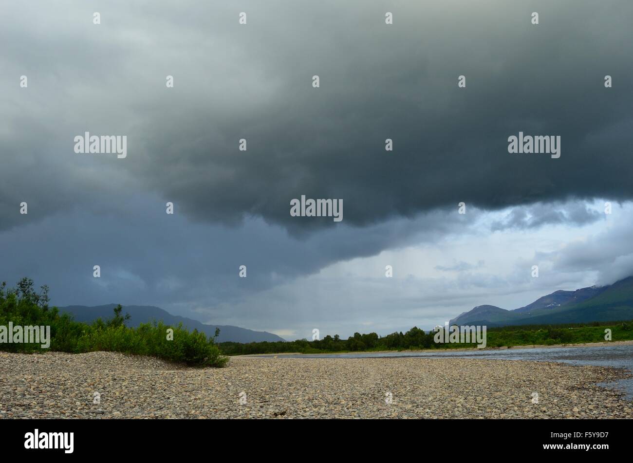 heavy summer thunderstorm coming in over mountain, forest and river ...