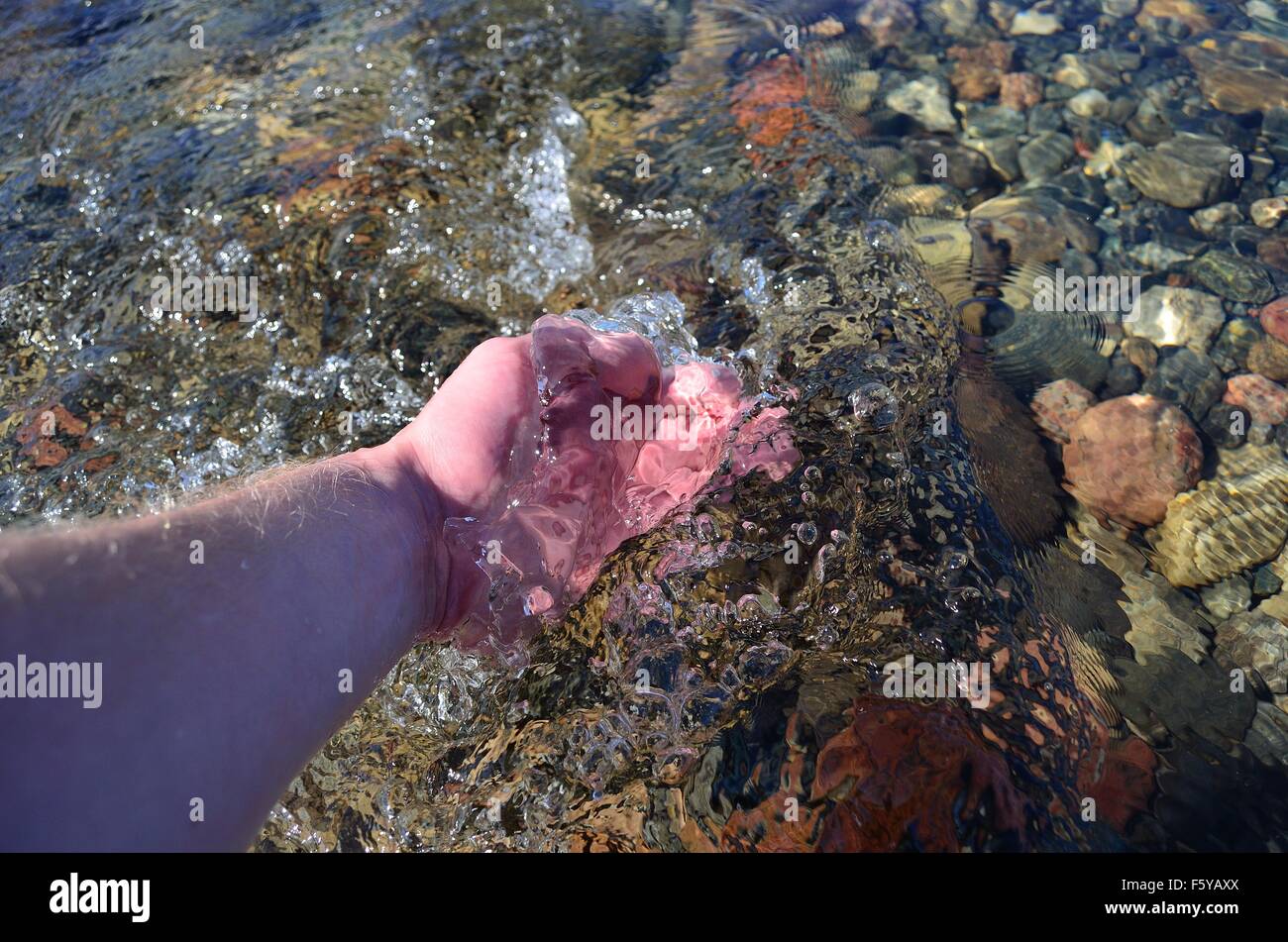 human hand scooping up clean fresh drinkable water from river stream ...