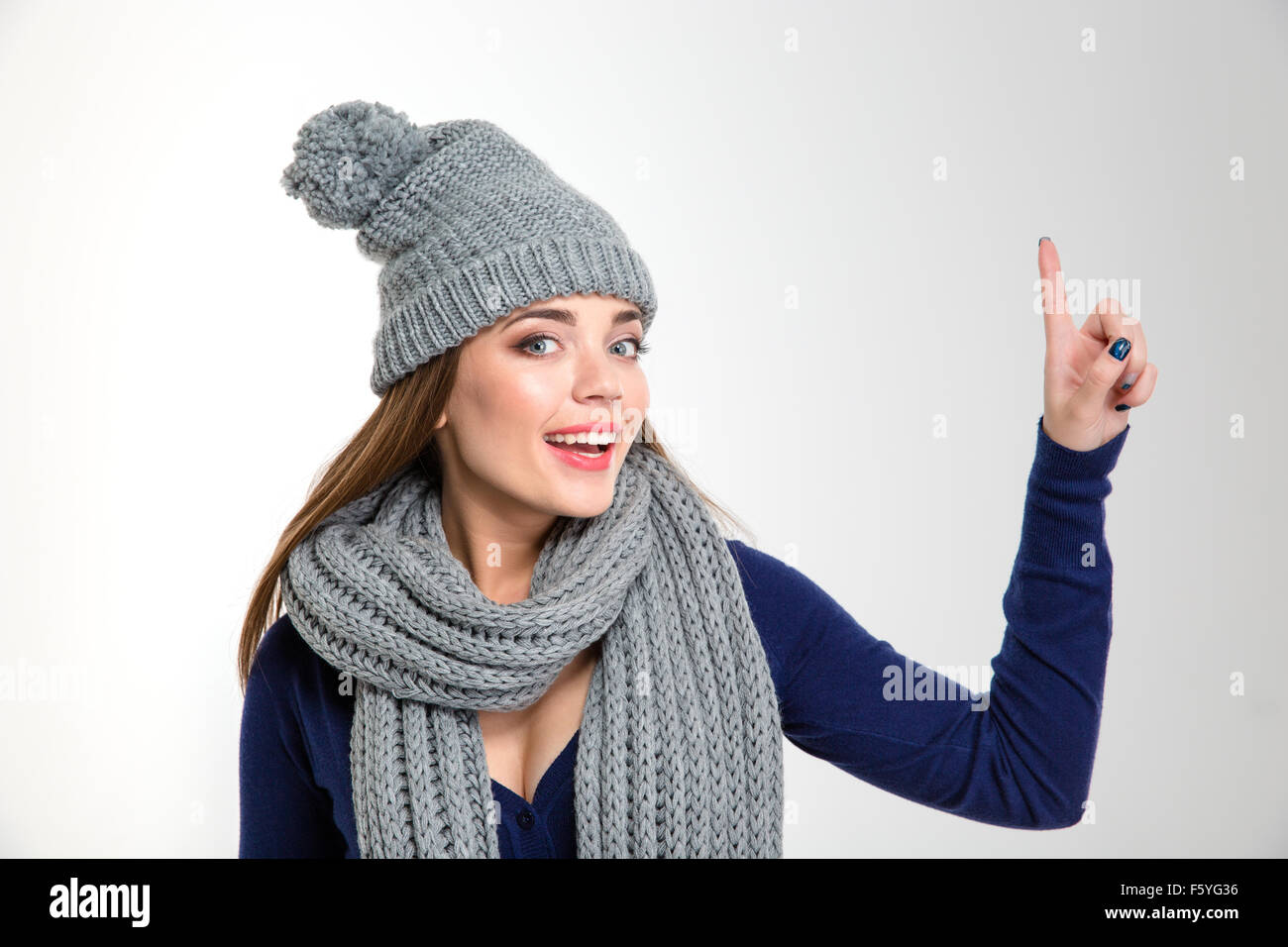 Portrait of a smiling woman wearing in scarf and hat pointing finger up ...