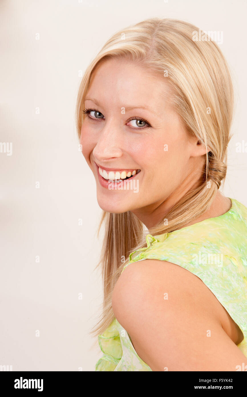A beautiful young woman is looking over her shoulder and smiling for ...
