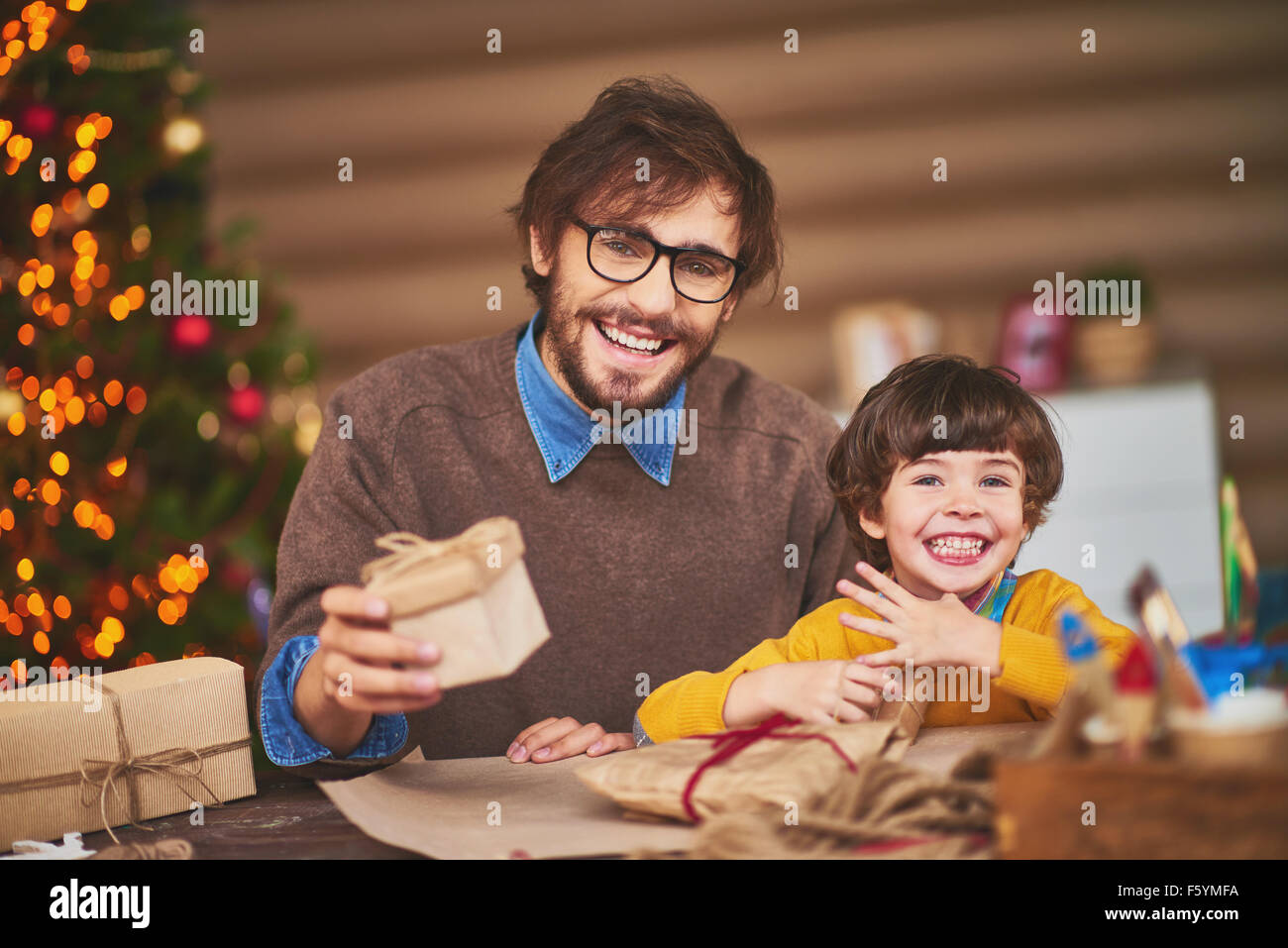 Happy young man and little boy wrapping gifts Stock Photo - Alamy