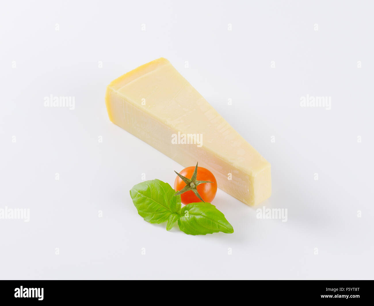 slice of parmesan cheese, cherry tomato an basil on white background ...
