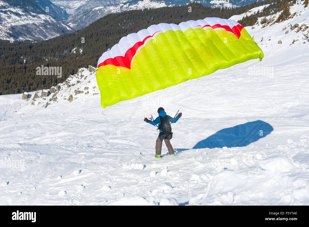 Paraglider taking off from a snow covered slope looking down an alpine ...