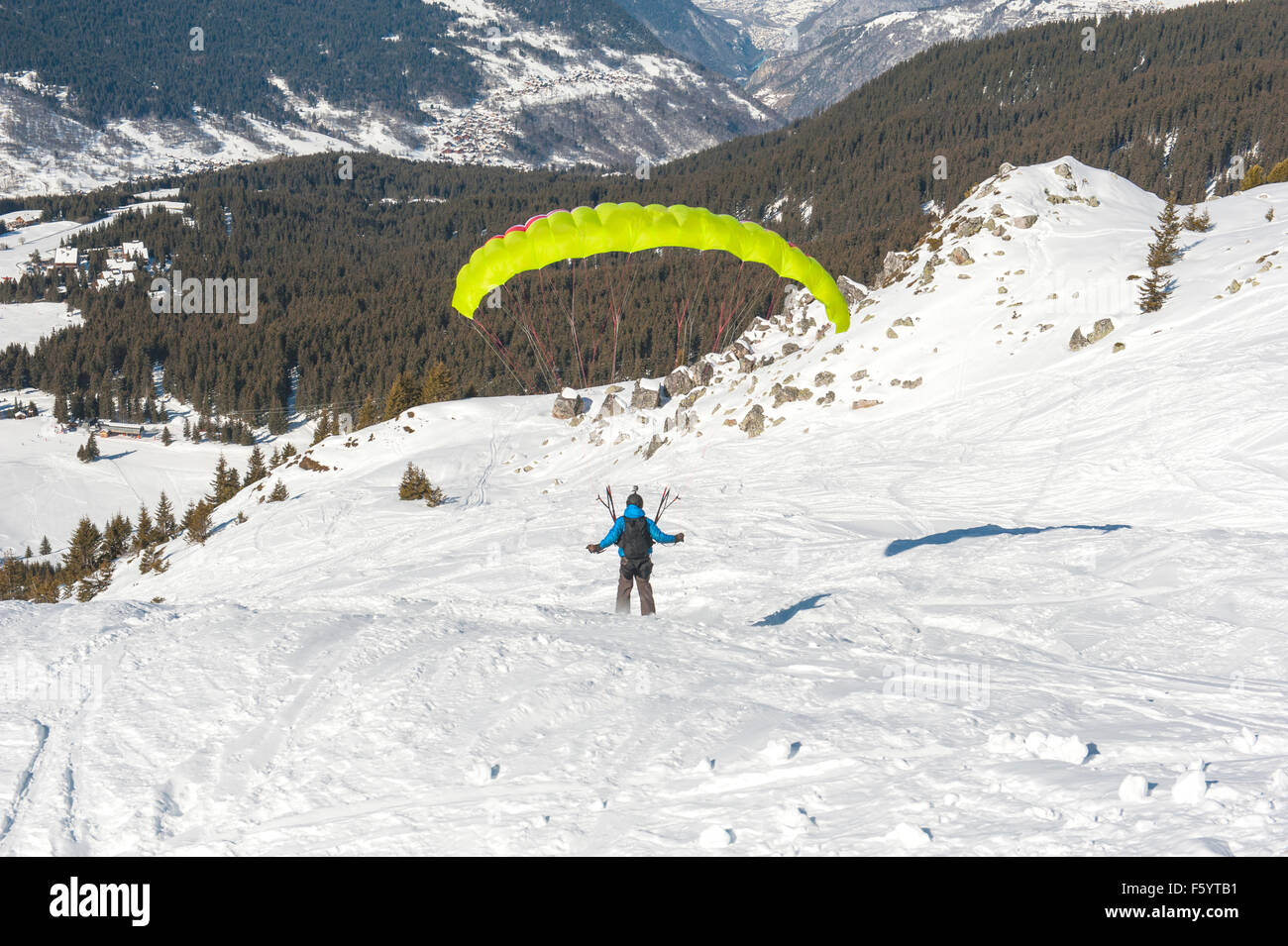 Paraglider taking off from a snow covered slope looking down an alpine ...