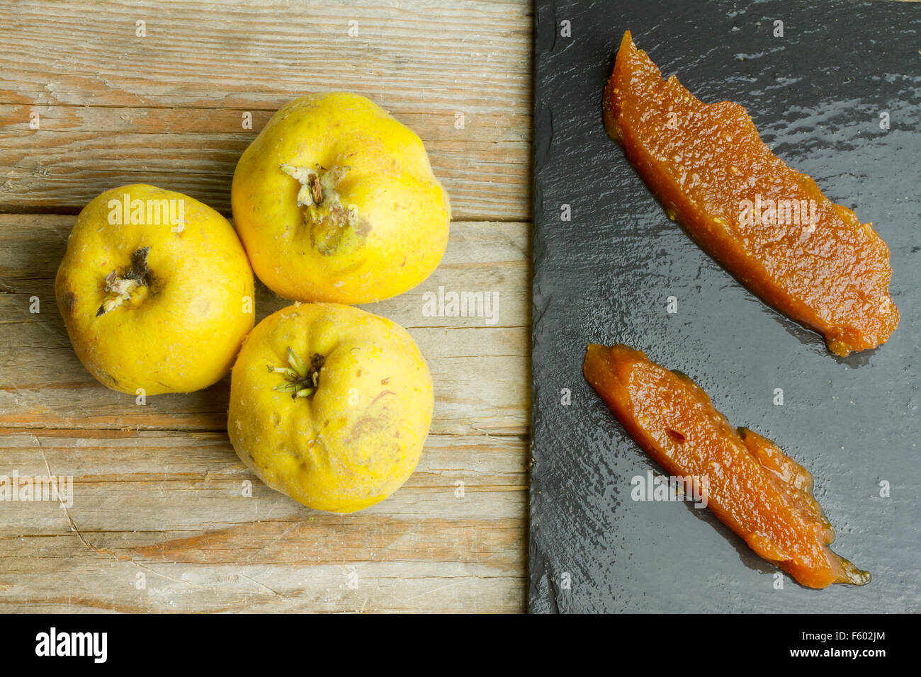 Spanish quince paste on a slate plate with three quince fruits on ...