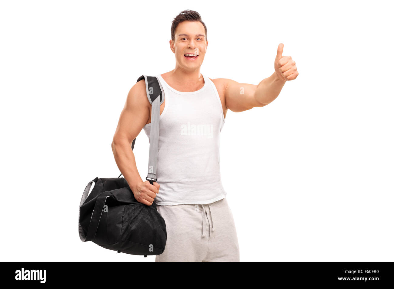 Muscular young man carrying a black sports bag and giving a thumb up ...