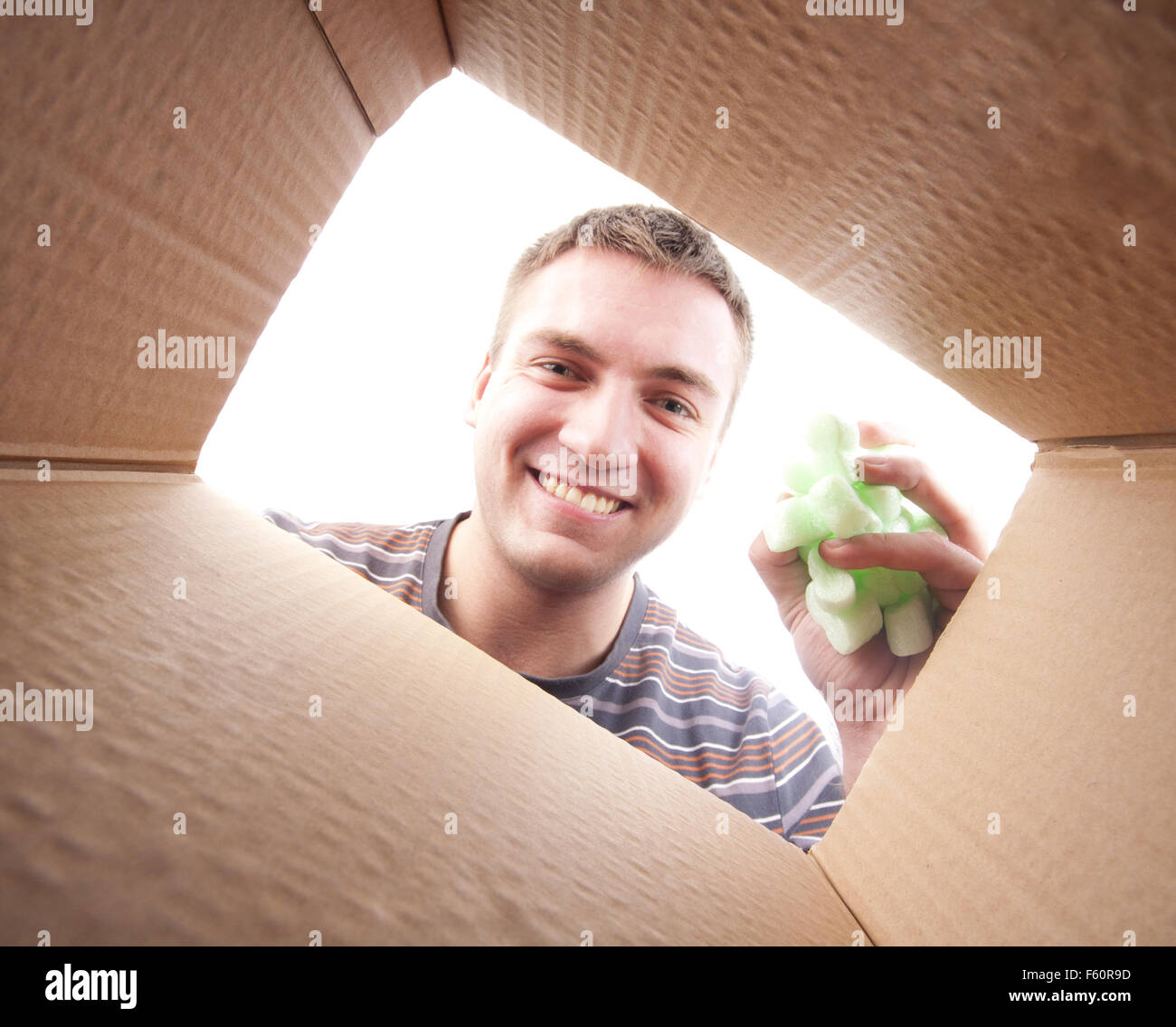 Young man throwing packing polyfoam into cardboard box Stock Photo - Alamy