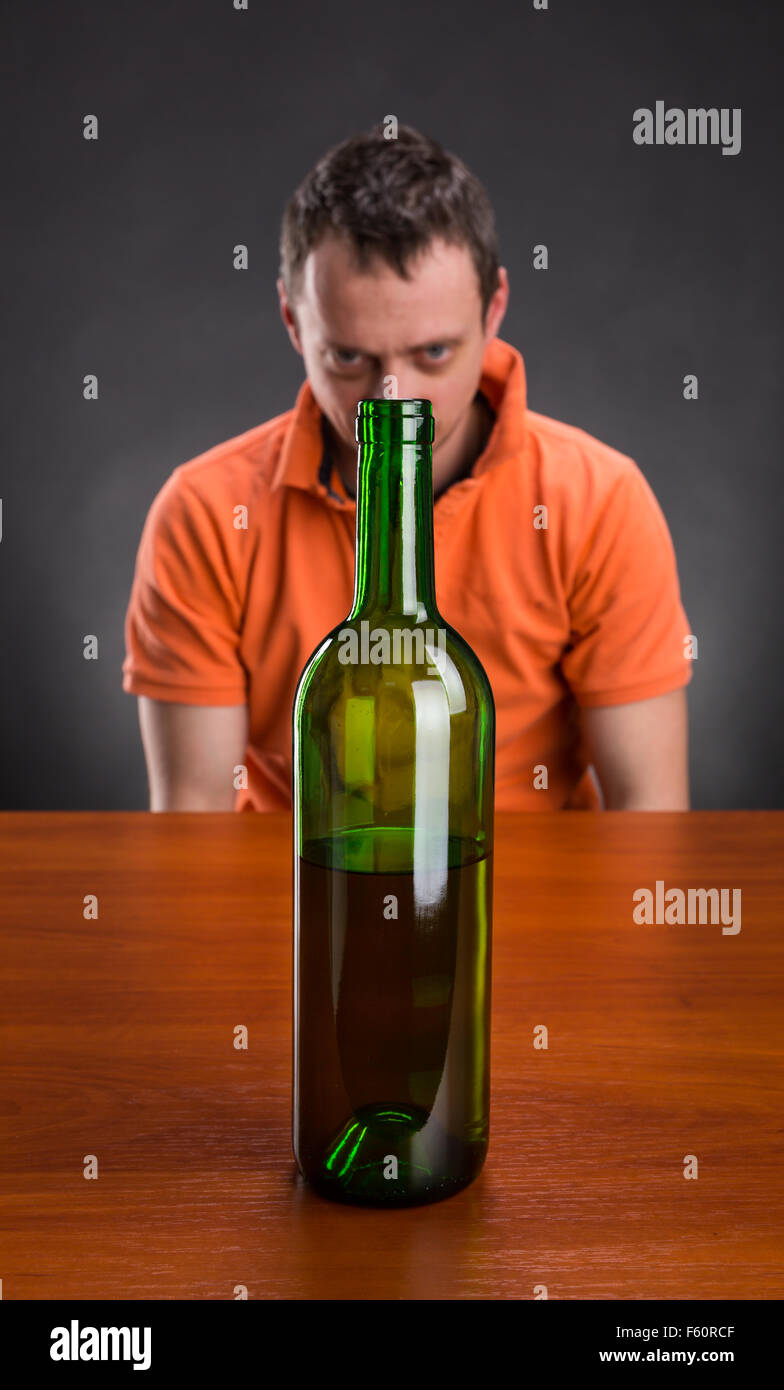 Alcohol addict looks at the bottle of wine Stock Photo - Alamy