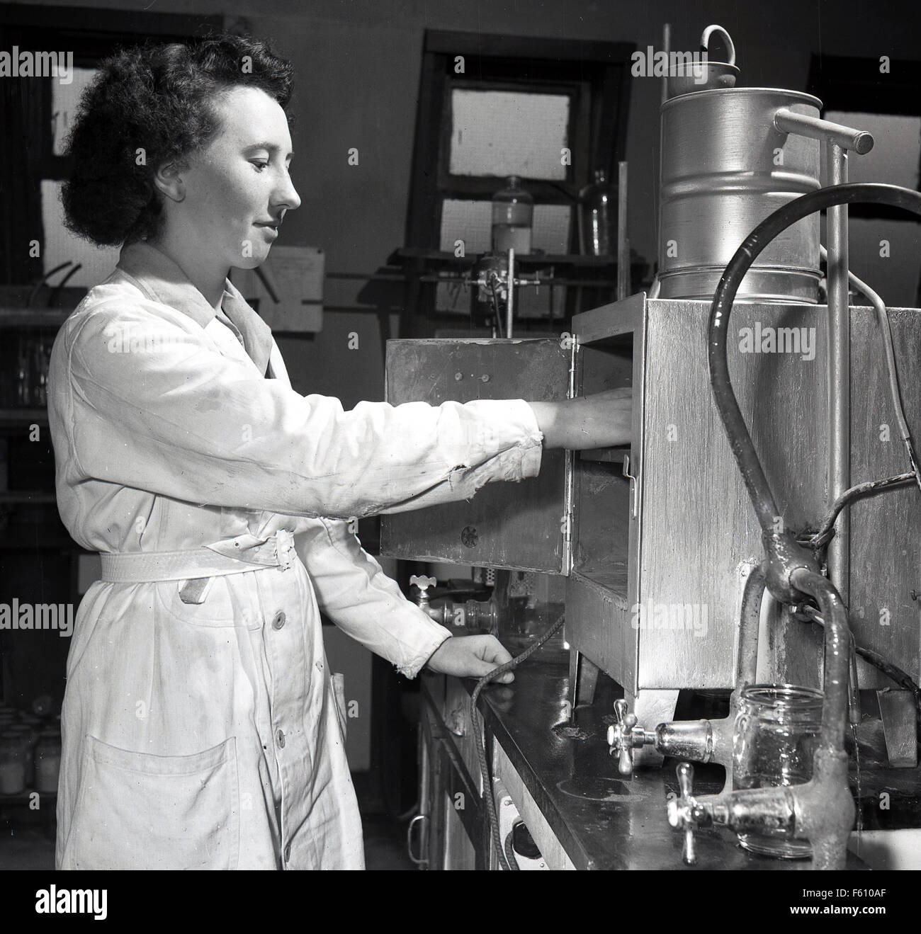 1950s historical picture, white coated young female adult student doing ...