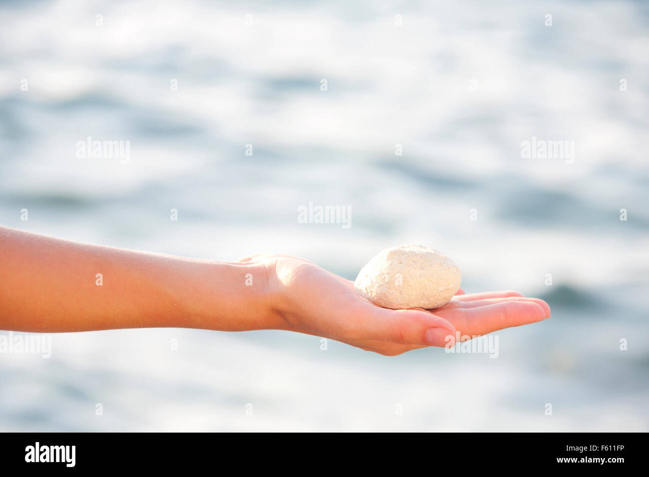 Seastone in palm of hand by the sea Stock Photo - Alamy