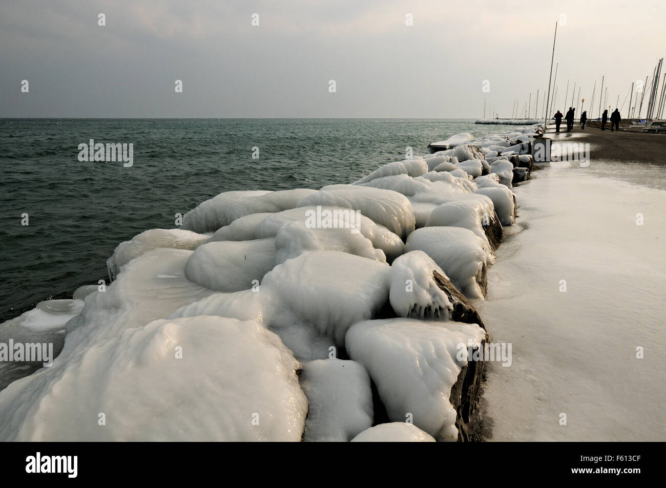 Ice-covered rocks and promenade along coast of Lake Geneva during the ...