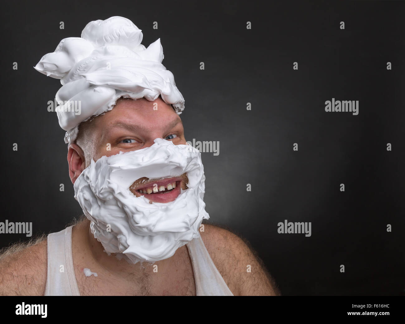 Bizarre smiling man with shaving foam on his face and on his head over ...