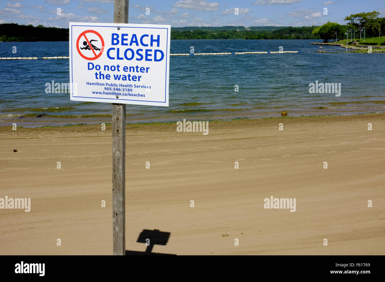 A beach closed sign on a sandy beach in the Canadian city of Hamilton ...