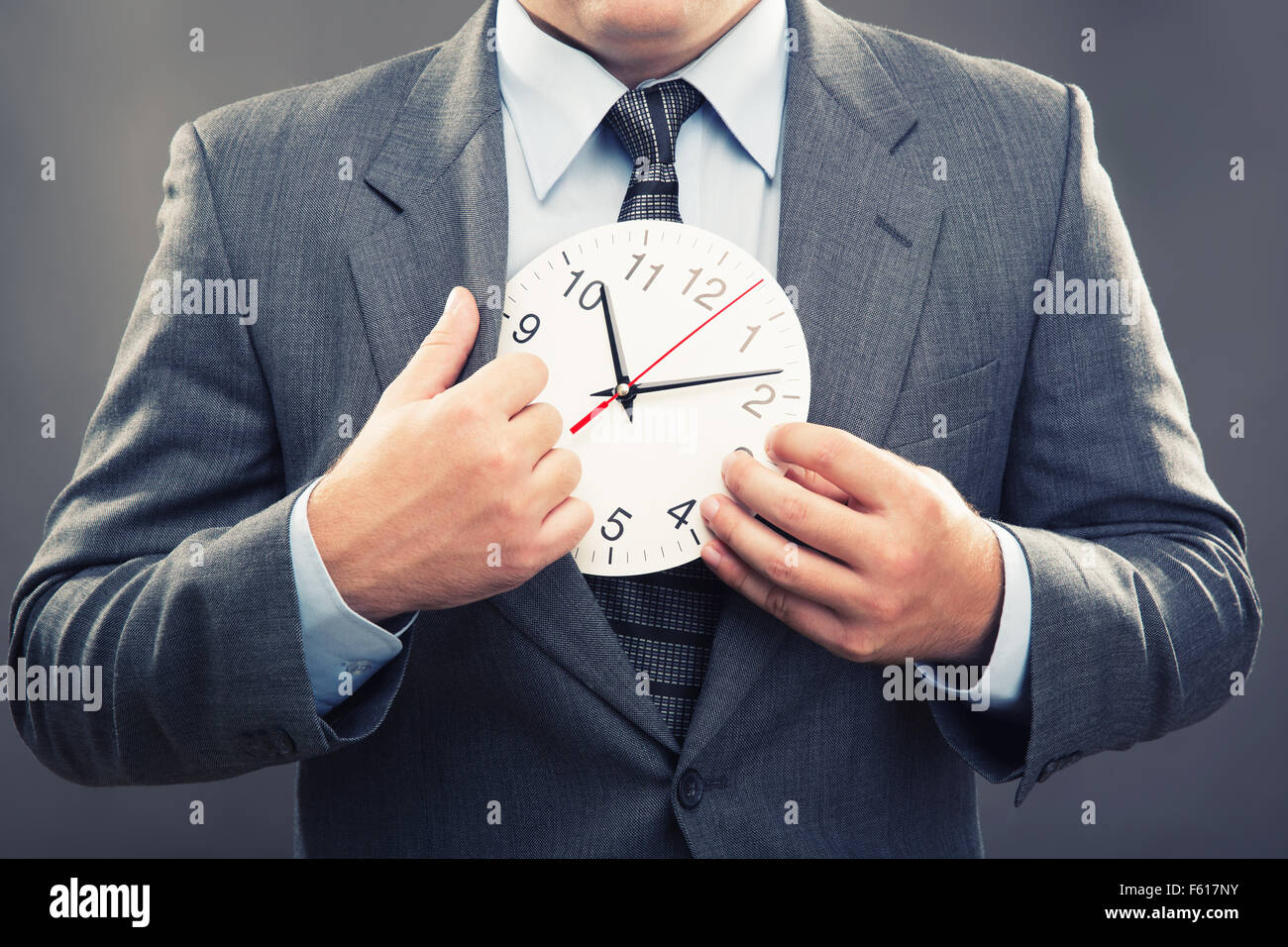Young man in a suit holding a clock Stock Photo - Alamy