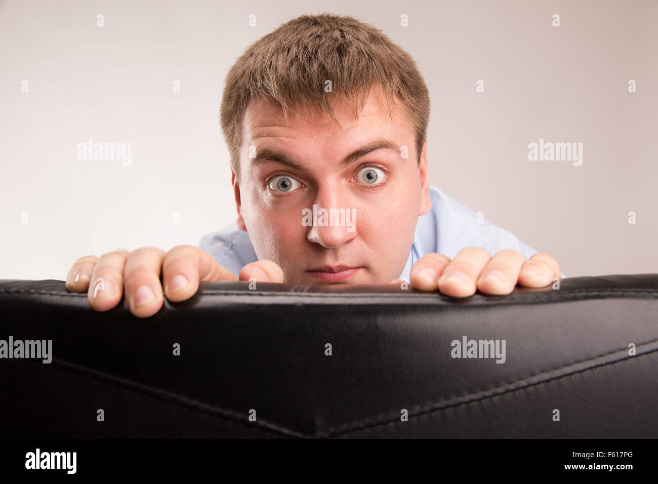 A young man hiding behind a office chair Stock Photo - Alamy