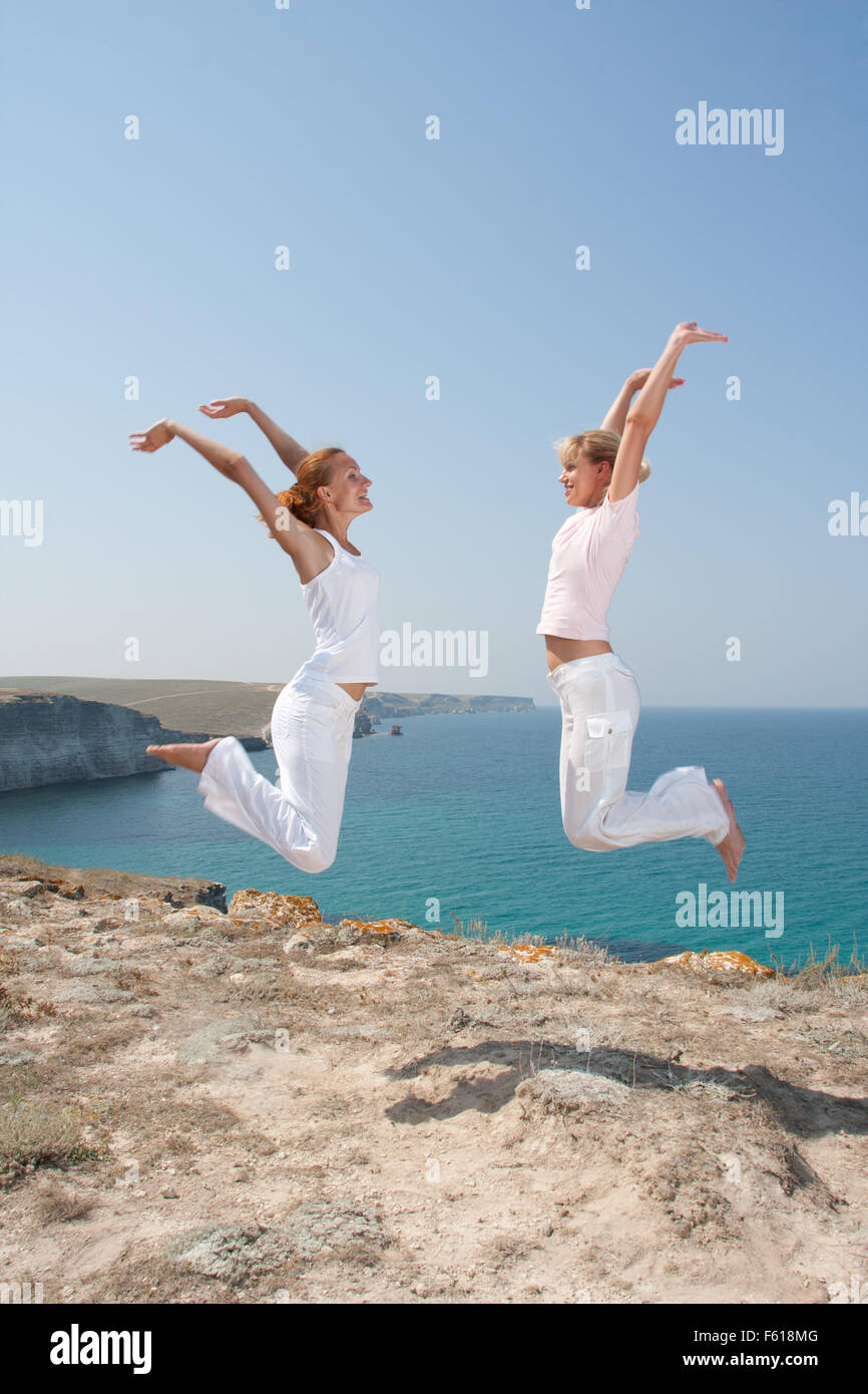 Two jumping women in white cloth against the sea Stock Photo - Alamy