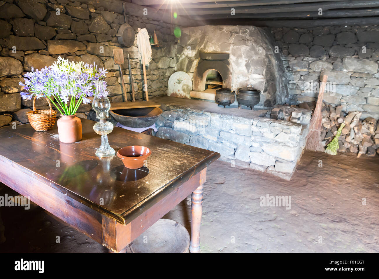 Ancient kitchen interior with furnace, pots and table with flowers ...